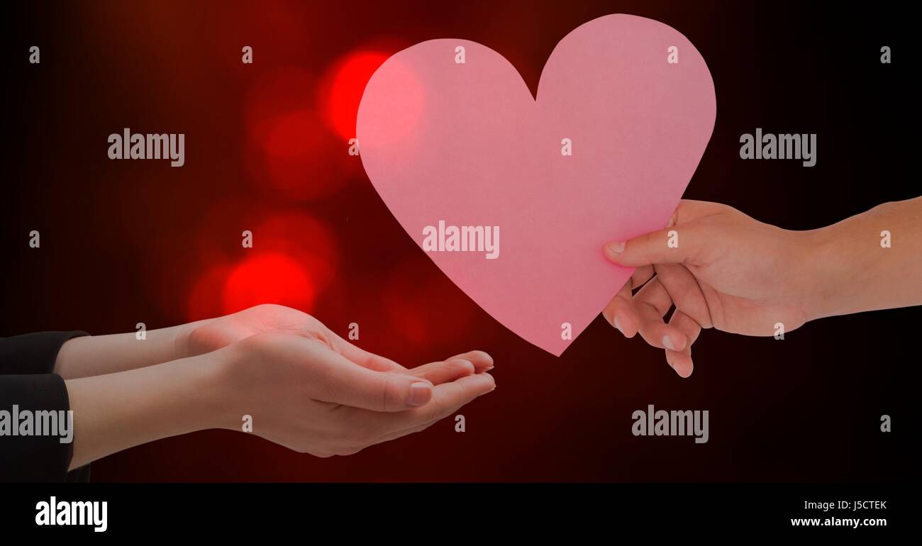 Digital composite of Hand giving heart shape to woman against red bokeh ...