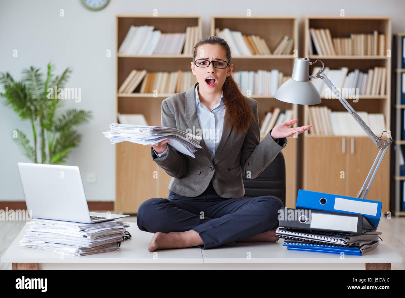 Busy angry businesswoman sitting on the desk in office Stock Photo - Alamy