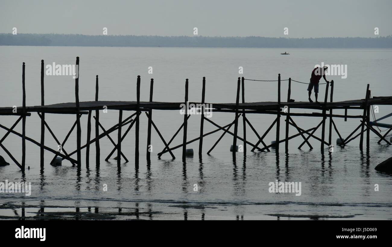 A man silhouetted with the poles of a make-shift dock early in the ...