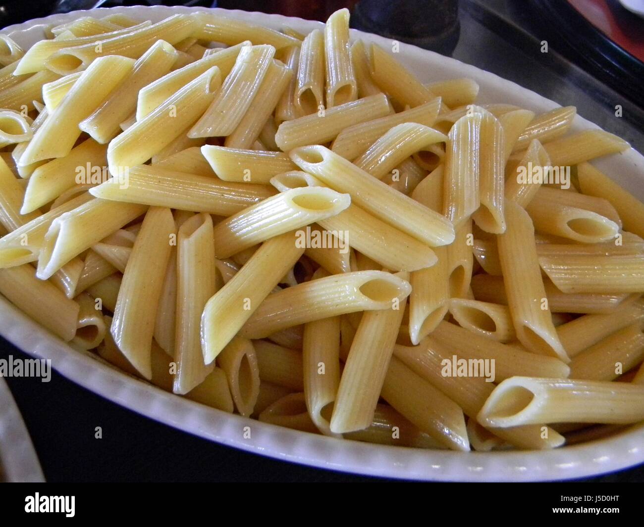 A plate of cooked penne pasta all ready to mix with sauces, meat and ...
