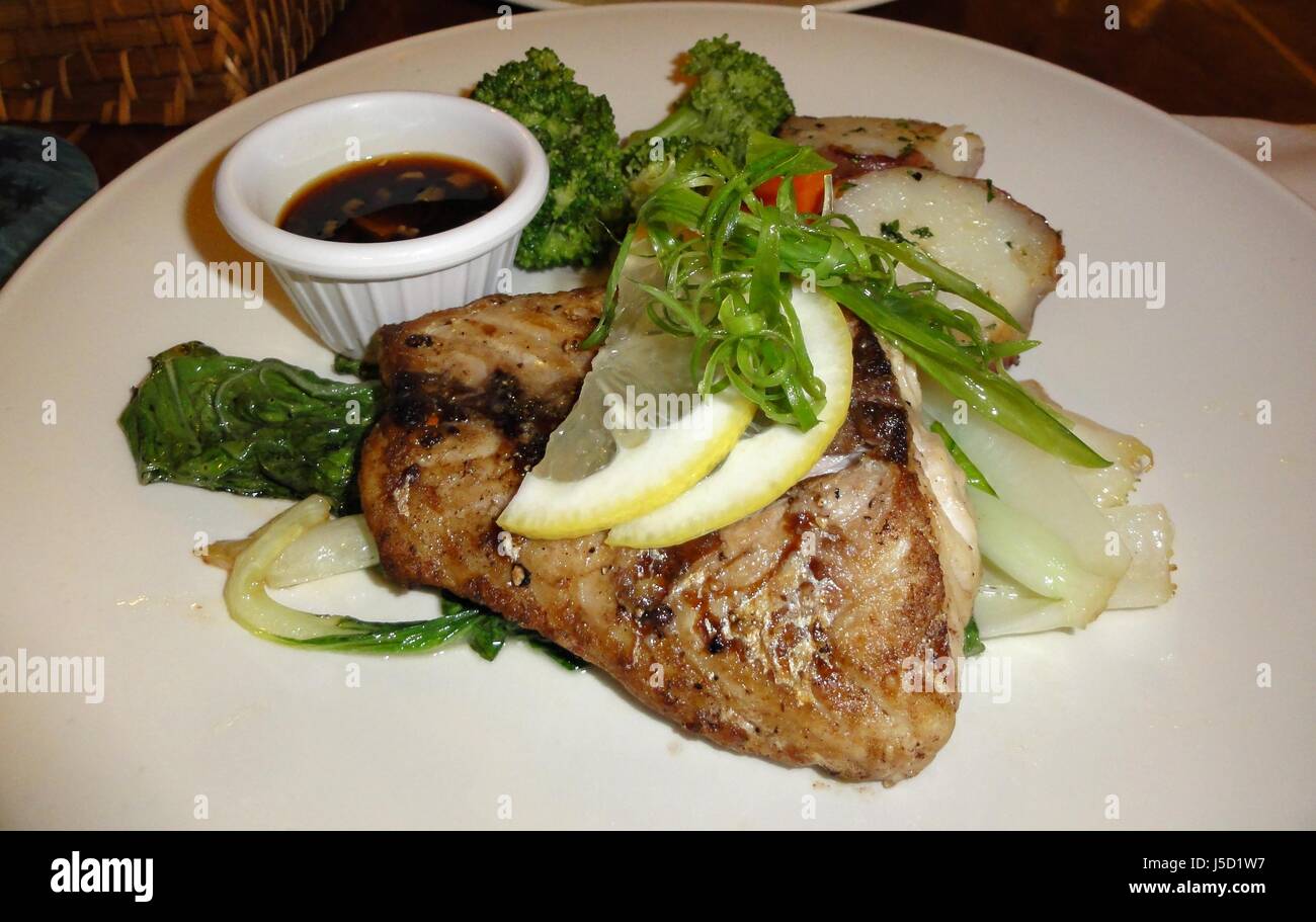 Grilled fish dinner A serving of grilled fish garnished with vegetables ...