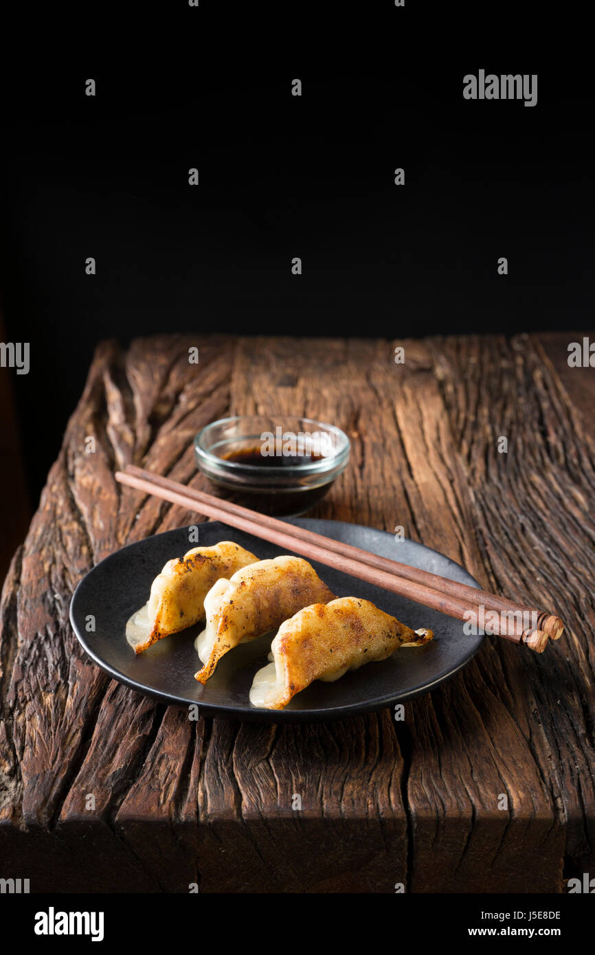 A plate of Japanese gyoza dumplings sitting on a rustic wooden table ...