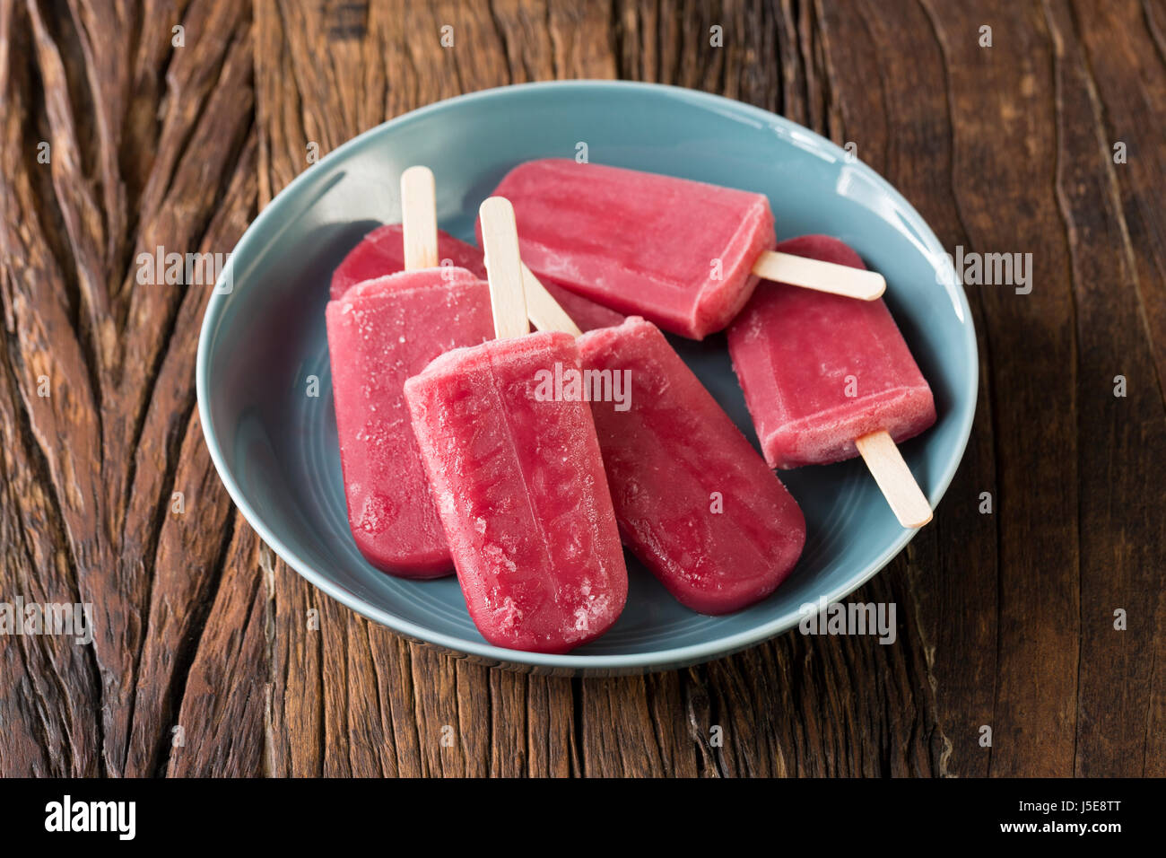 Homemade Raspberry and vanilla ice pops on a rustic wood background ...