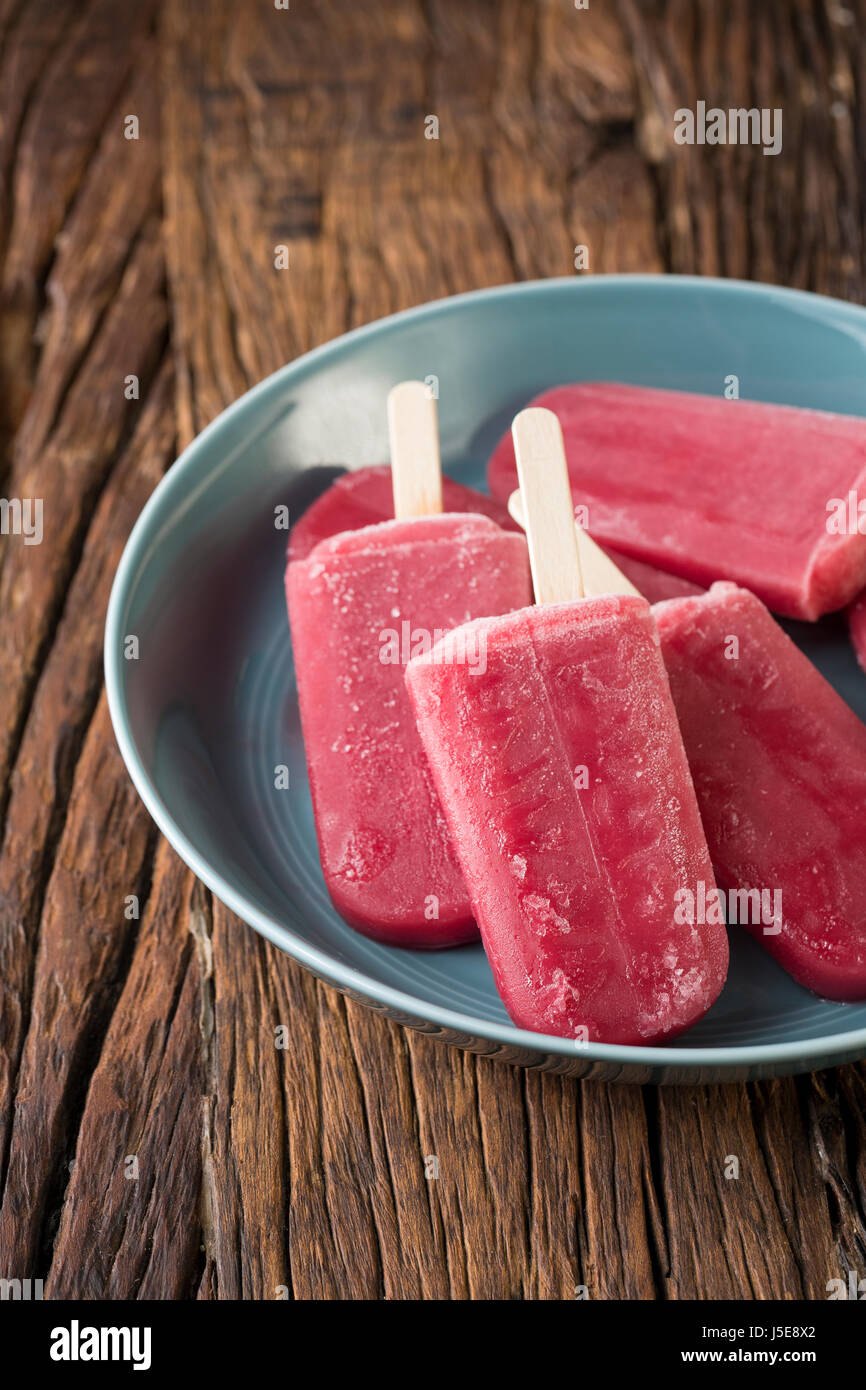 Homemade Raspberry and vanilla ice pops on a rustic wood background ...