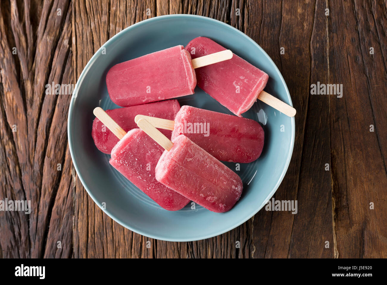 Homemade Raspberry and vanilla ice pops on a rustic wood background ...