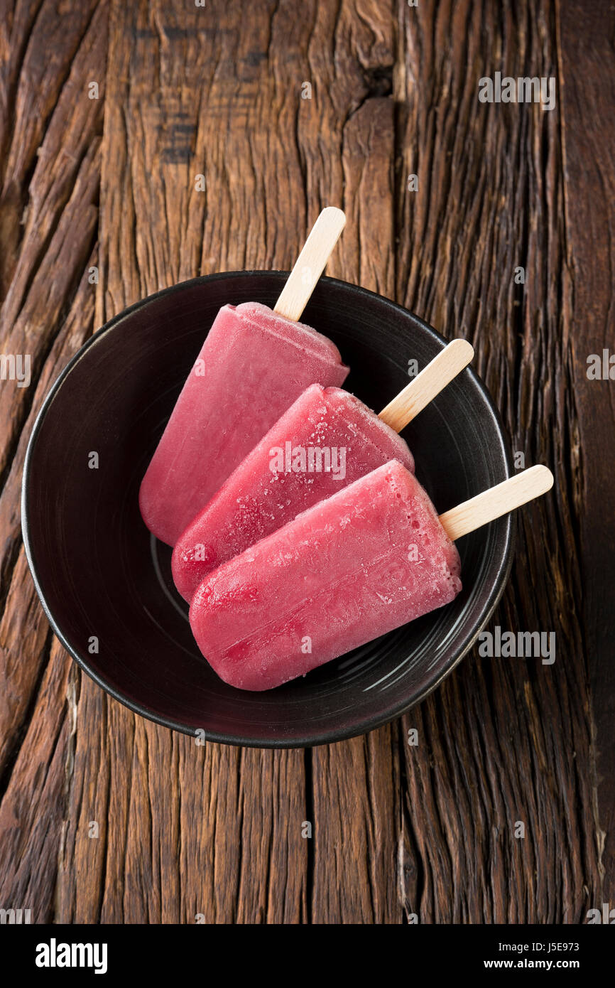 Three Homemade Raspberry and vanilla ice pops on a rustic wood ...