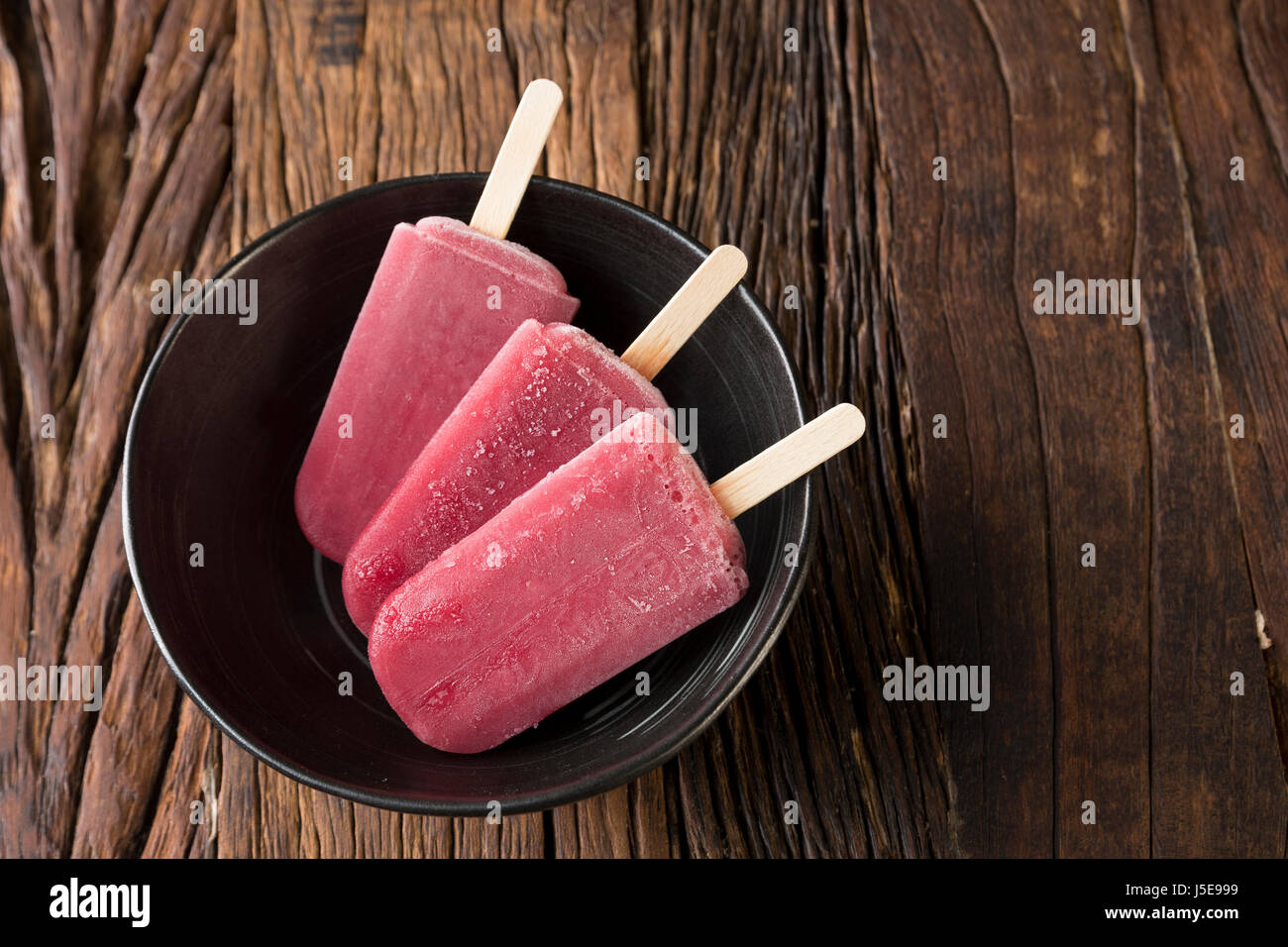 Three Homemade Raspberry and vanilla ice pops on a rustic wood ...