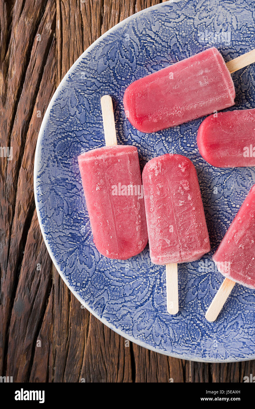 Homemade Raspberry and vanilla ice pops on a rustic wood background ...