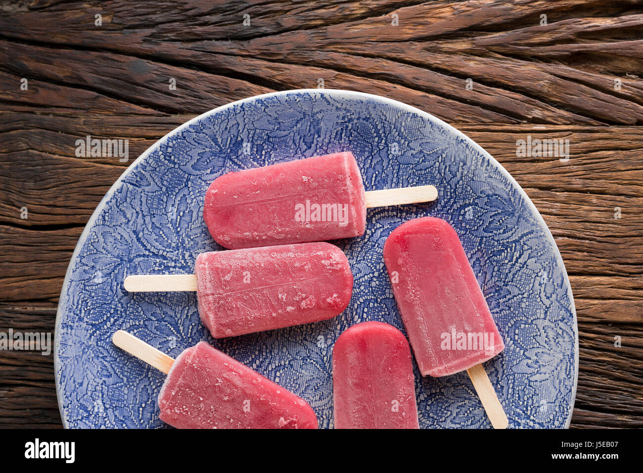 Homemade Raspberry and vanilla ice pops on a rustic wood background ...