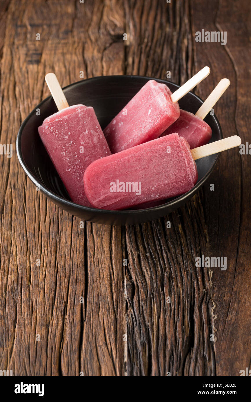 Three Homemade Raspberry and vanilla ice pops on a rustic wood ...