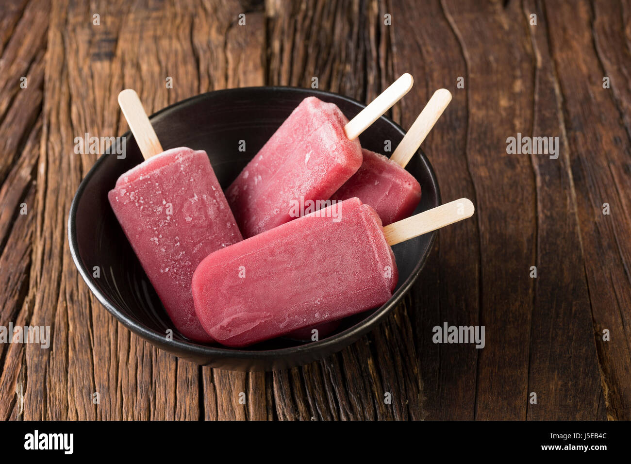 Three Homemade Raspberry and vanilla ice pops on a rustic wood ...