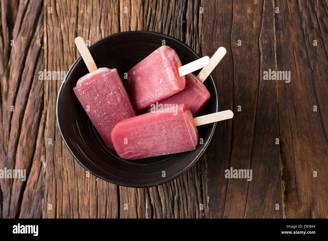 Three Homemade Raspberry and vanilla ice pops on a rustic wood ...