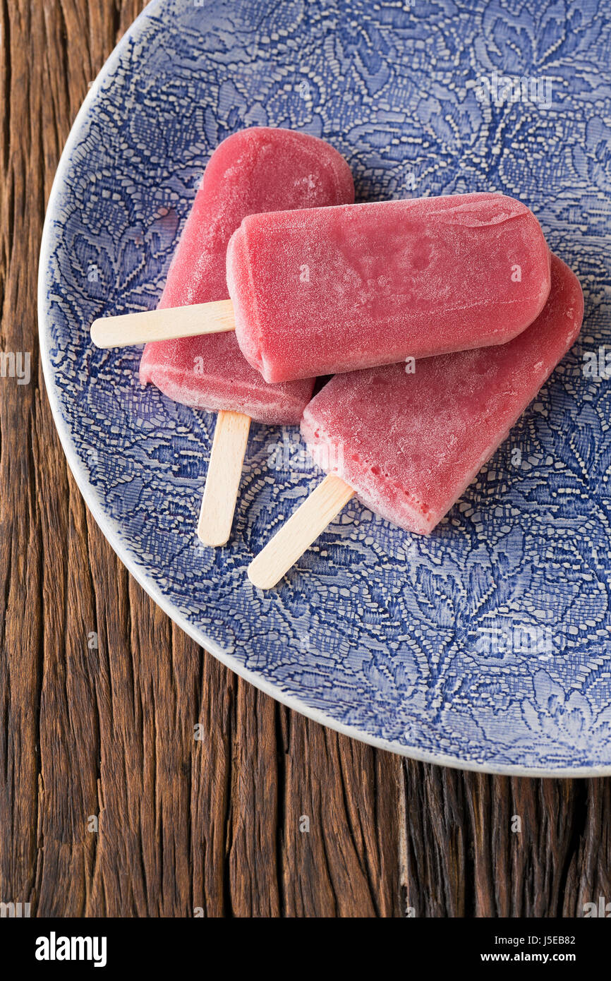 Homemade Raspberry and vanilla ice pops on a rustic wood background ...
