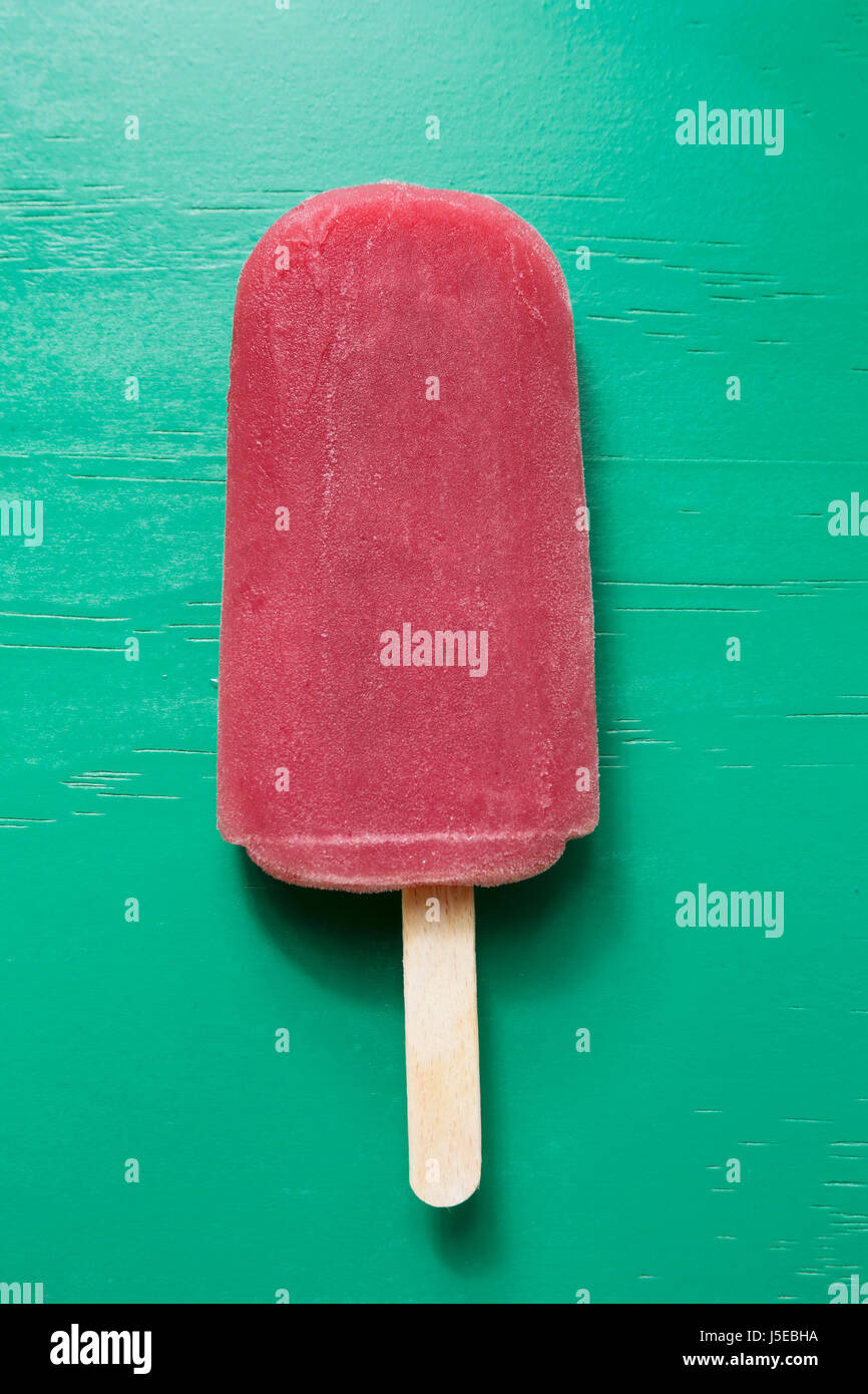 Homemade Raspberry and vanilla ice pops on a green wooden background ...