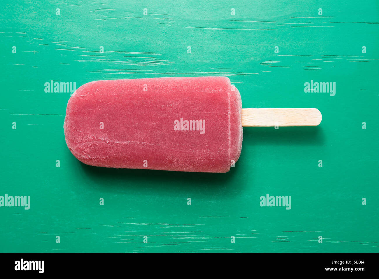 Homemade Raspberry and vanilla ice pops on a green wooden background ...