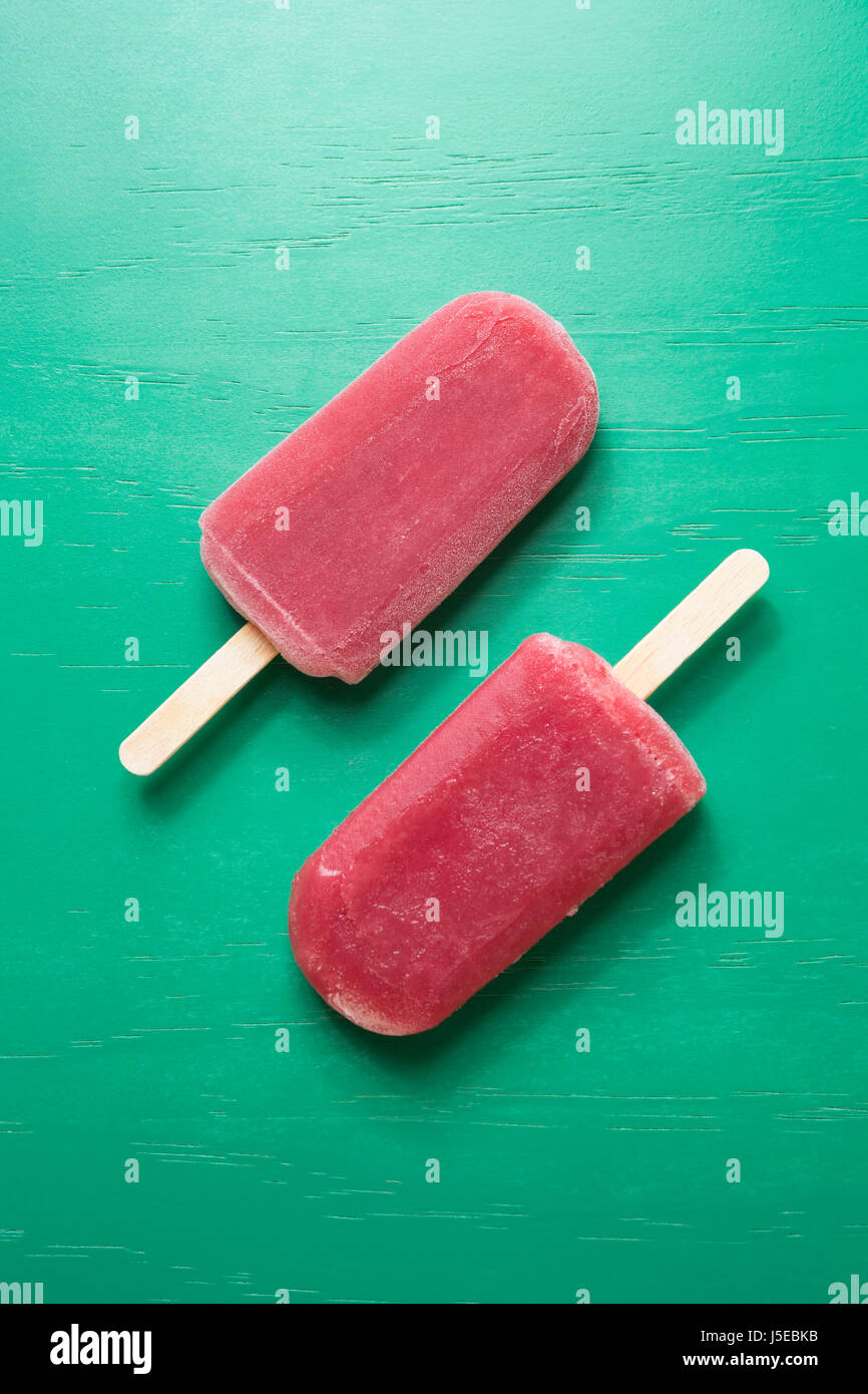 Two Homemade Raspberry and vanilla ice pops on a green wooden ...