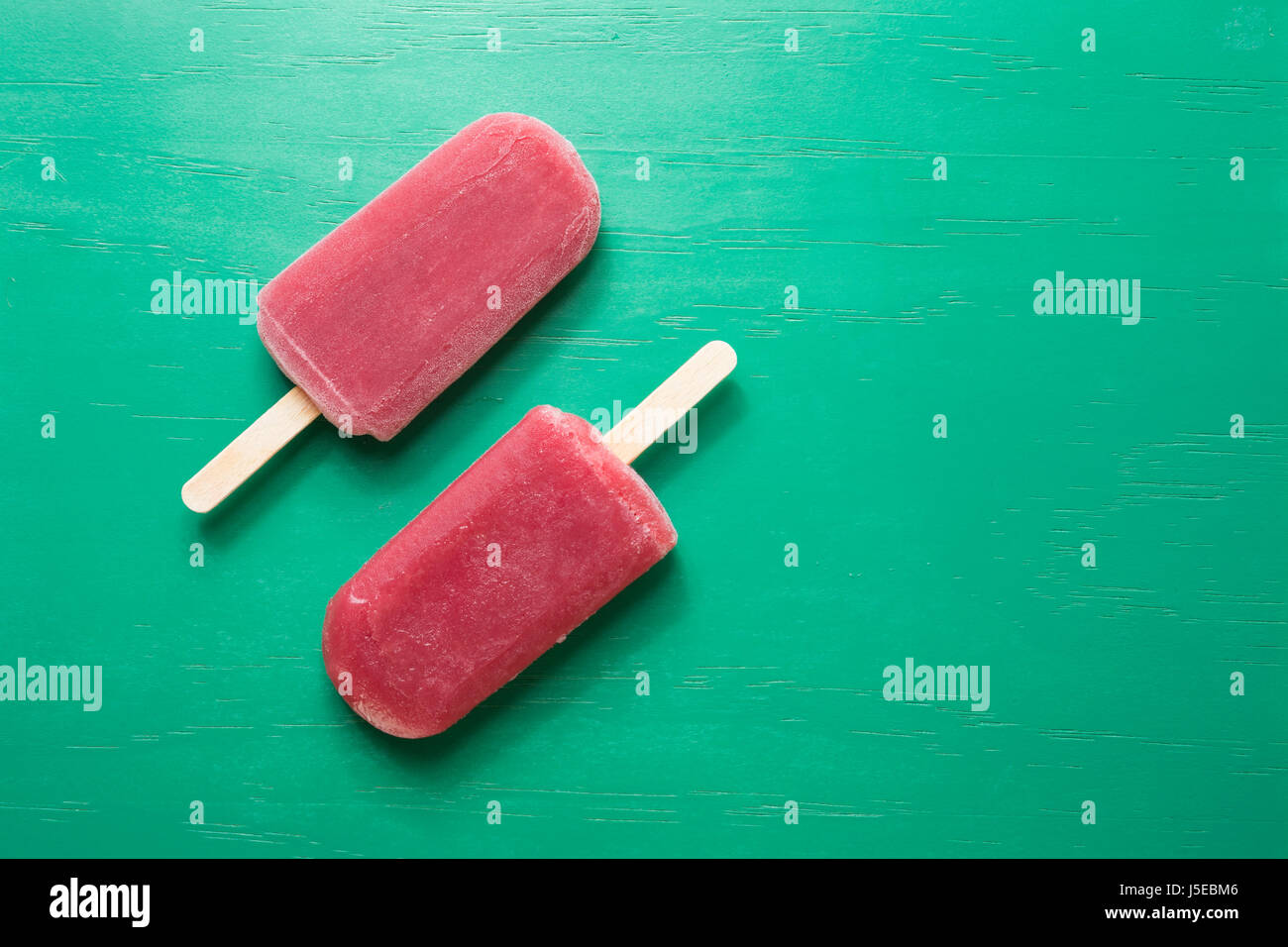 Two Homemade Raspberry and vanilla ice pops on a green wooden ...