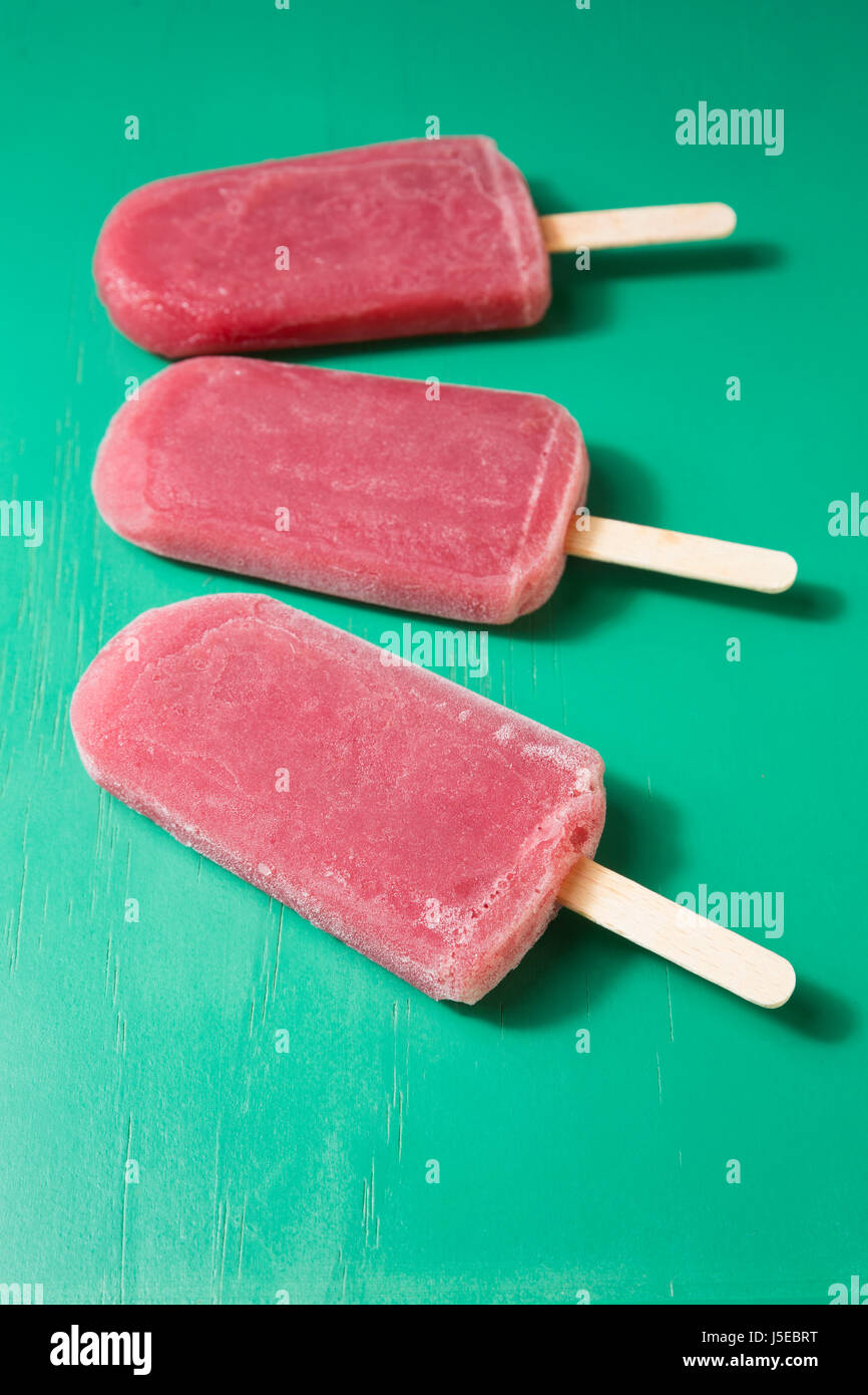 Three Homemade Raspberry and vanilla ice pops on a green wooden ...