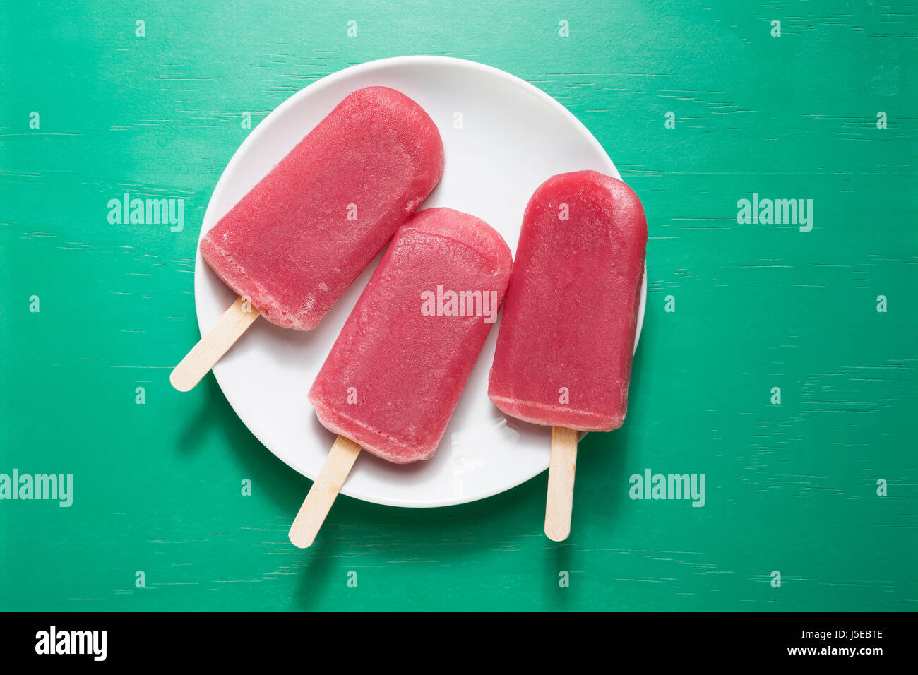 Three Homemade Raspberry and vanilla ice pops on a green wooden ...