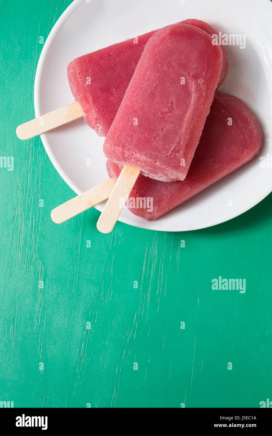 Homemade Raspberry and vanilla ice pops on a rustic wood background ...