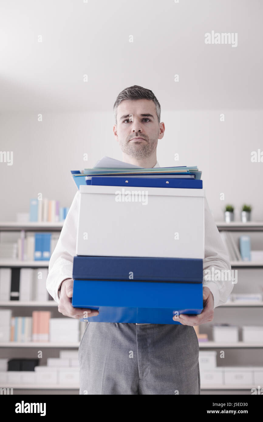 Confident businessman carrying boxes and paperwork in the office Stock ...