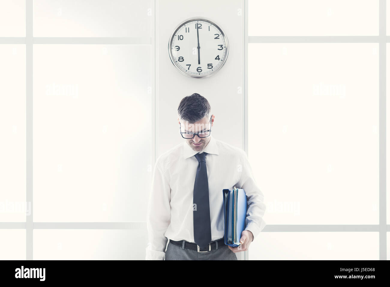 Frustrated businessman in the office standing under a clock ...