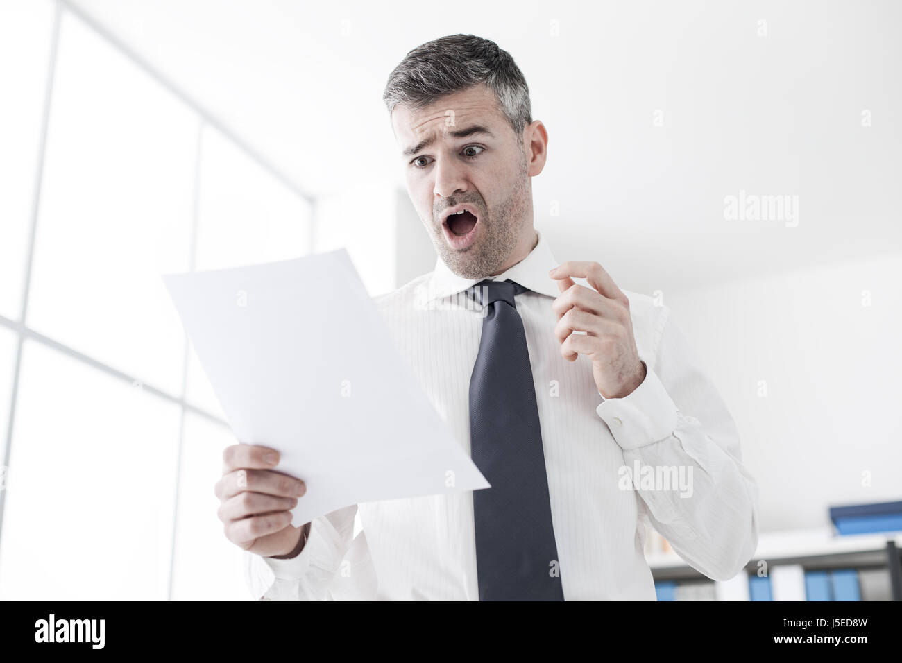 Businessman in the office receiving shocking bills and tax documents ...