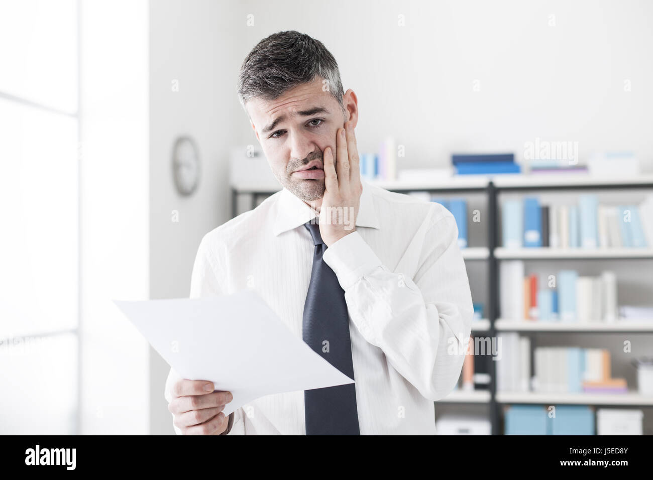 Desperate businessman in the office receiving expensive bills, business ...