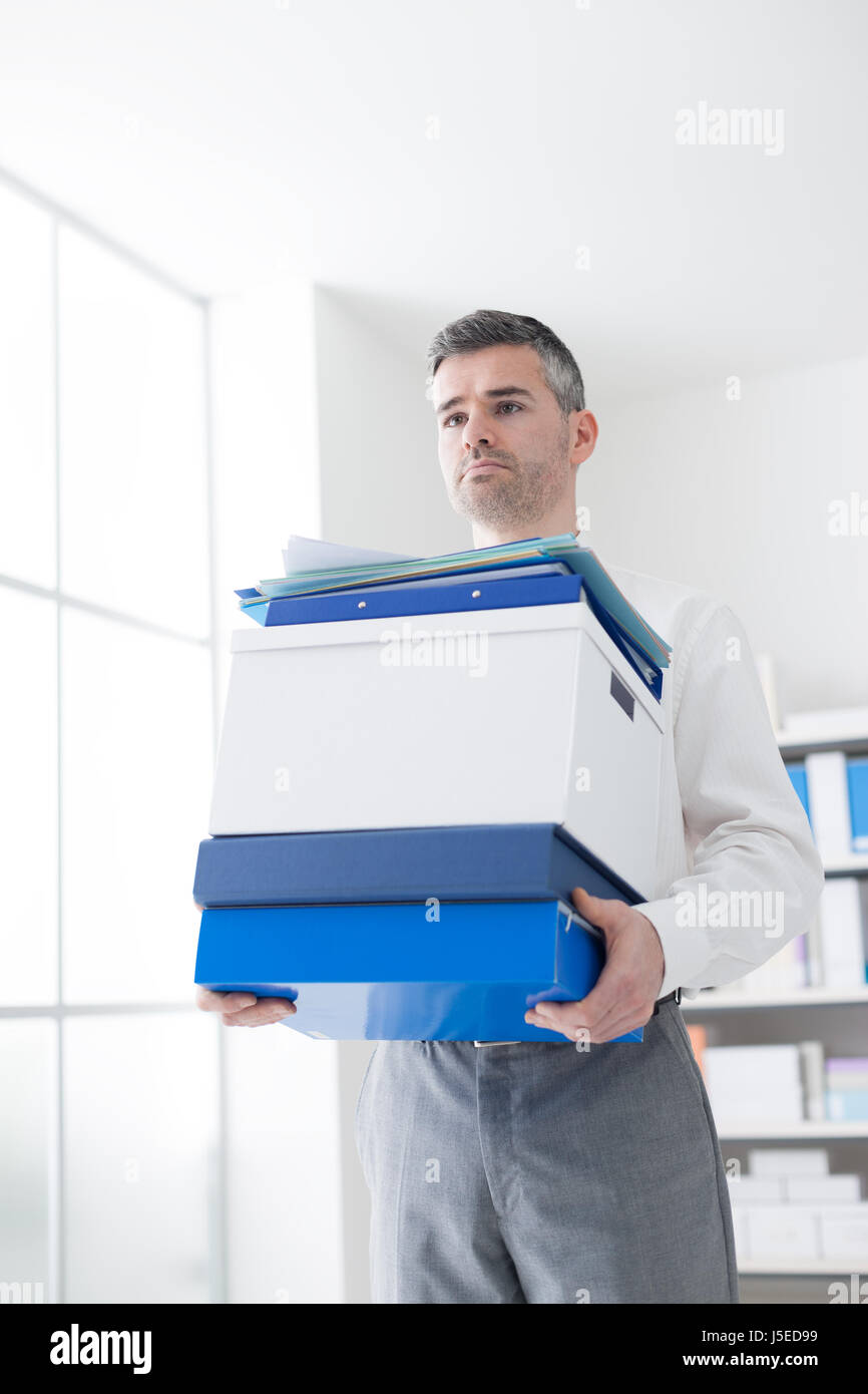 Confident businessman carrying boxes and paperwork in the office Stock ...