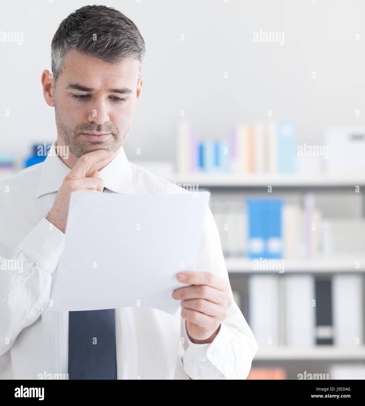 Confident businessman reading a contract or insurance policy and ...