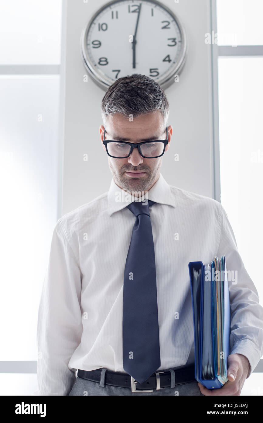 Frustrated businessman in the office standing under a clock ...