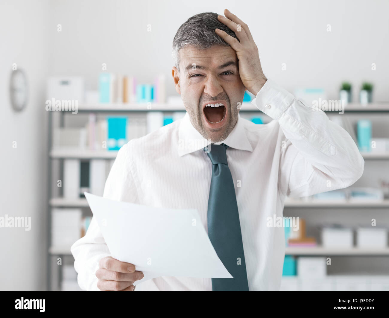 Businessman in the office receiving shocking bills and tax documents ...