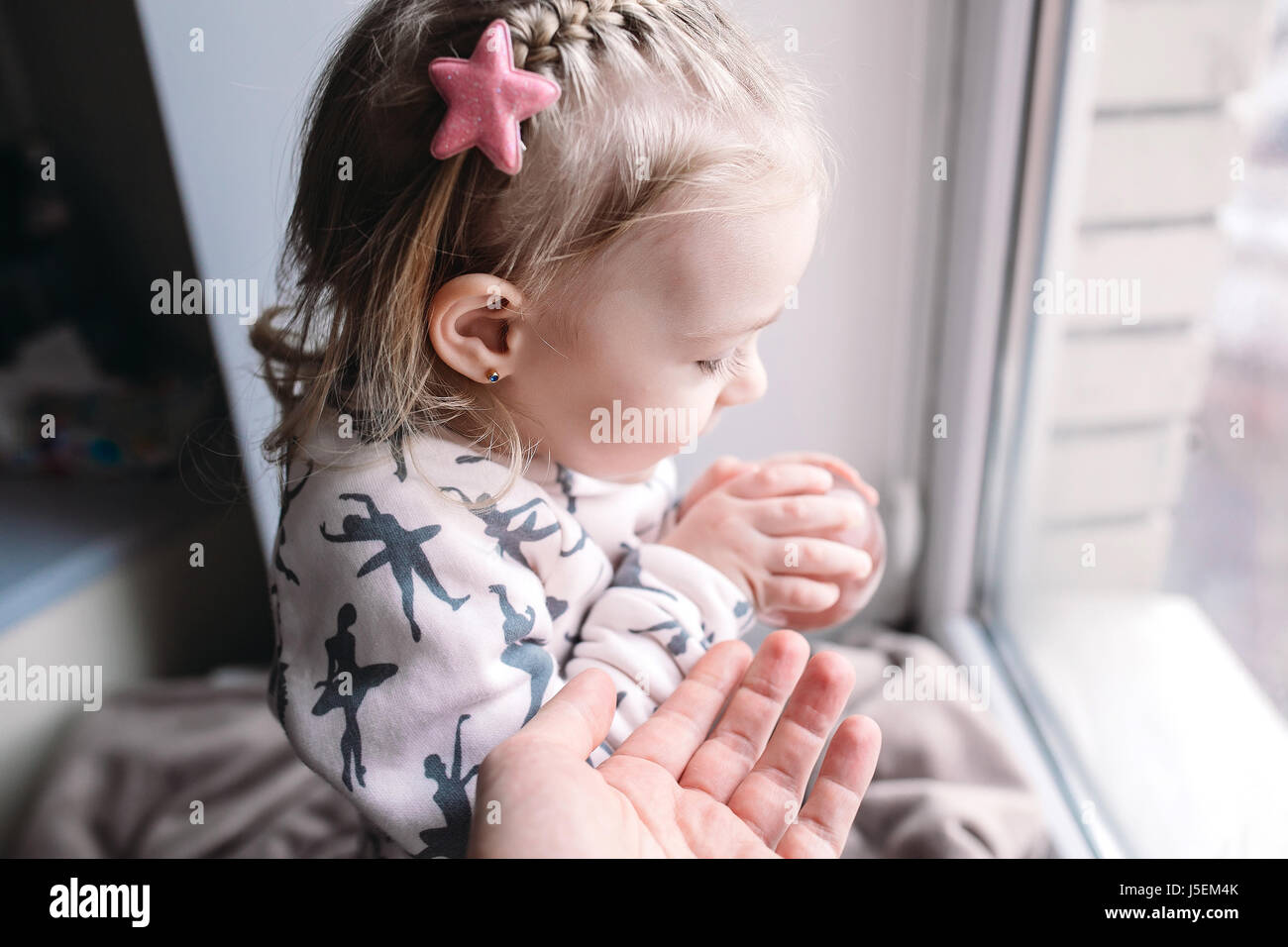 Little girl sitting near the window Stock Photo - Alamy
