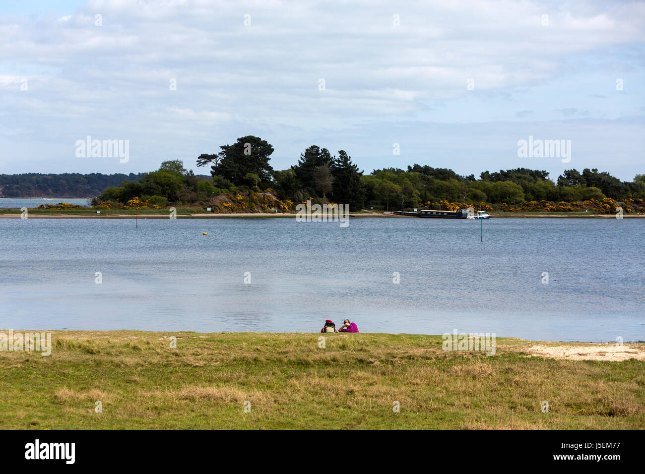 Couple lying on the beach with the Wych channel from Arne RSPB reserve ...