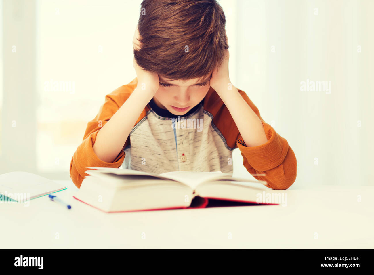 student boy reading book or textbook at home Stock Photo - Alamy