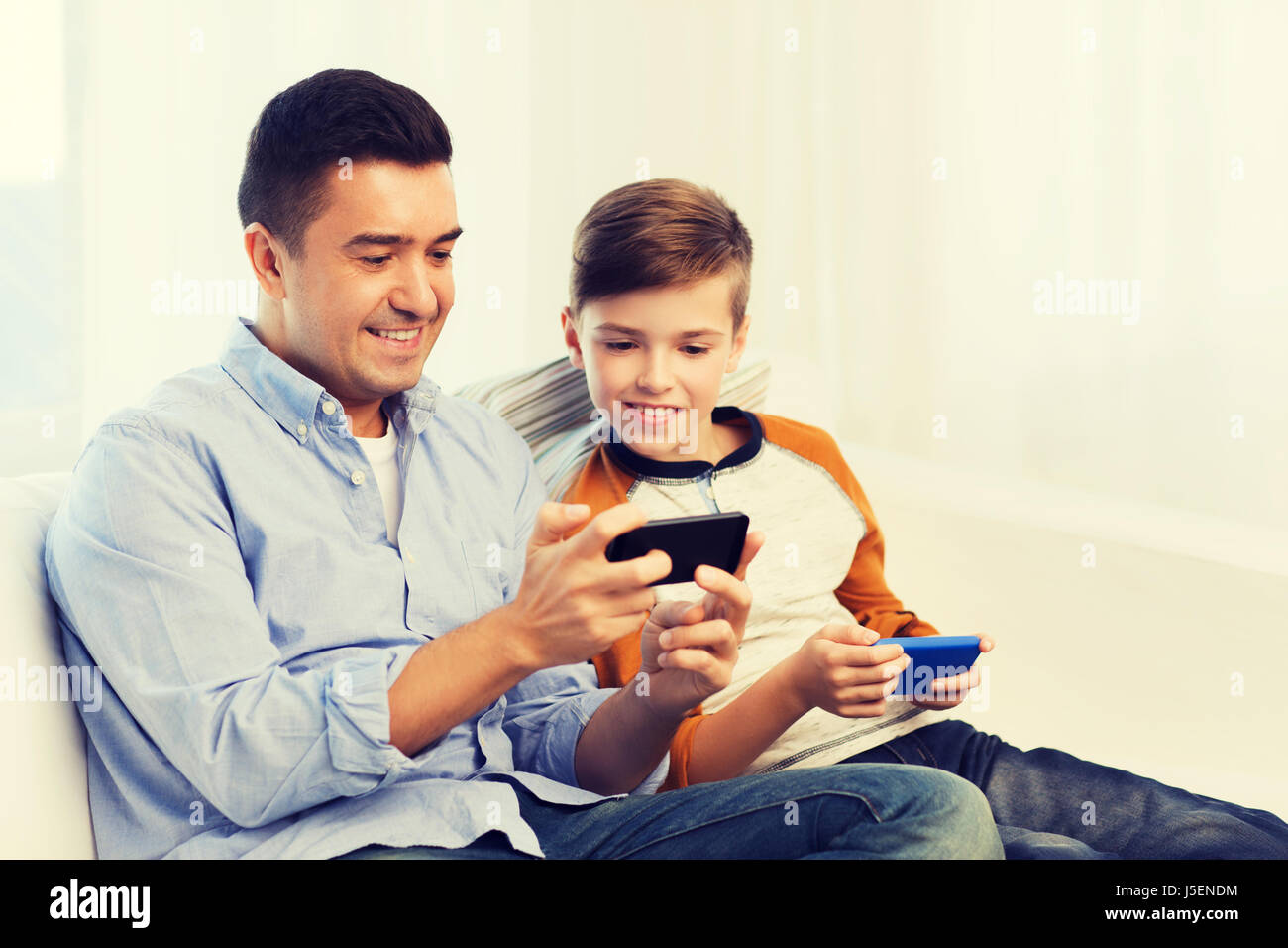 happy father and son with smartphones at home Stock Photo - Alamy