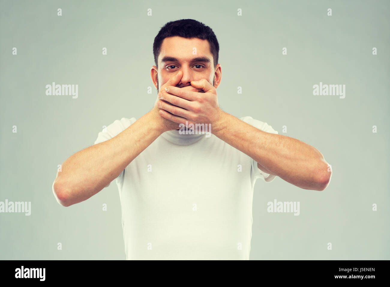 man in white t-shirt covering his mouth with hands Stock Photo - Alamy
