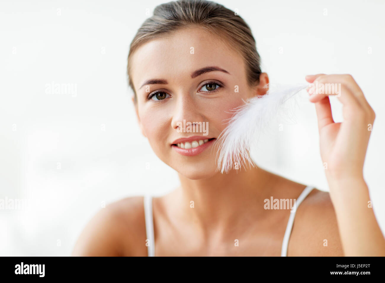 beautiful woman with feather touching her face Stock Photo - Alamy