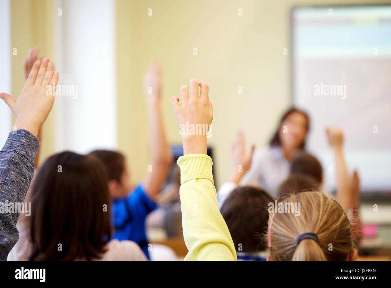 group of school kids raising hands in classroom Stock Photo - Alamy