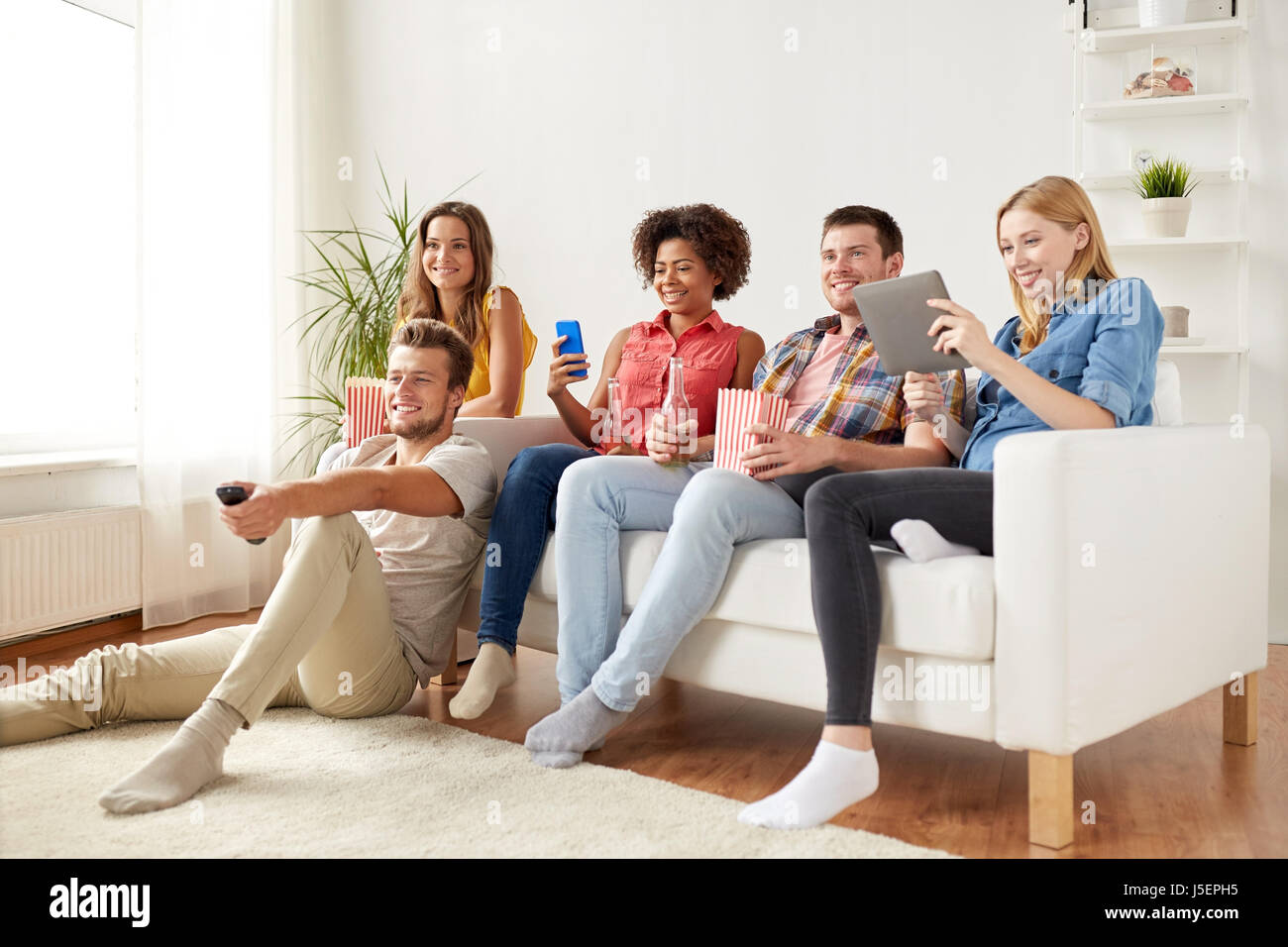 friends with gadgets and beer watching tv at home Stock Photo - Alamy