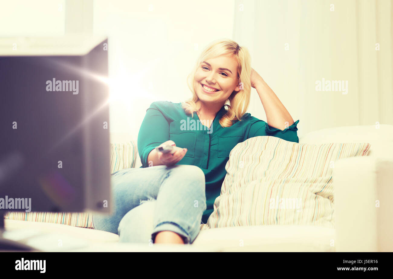 smiling woman with remote watching tv at home Stock Photo - Alamy