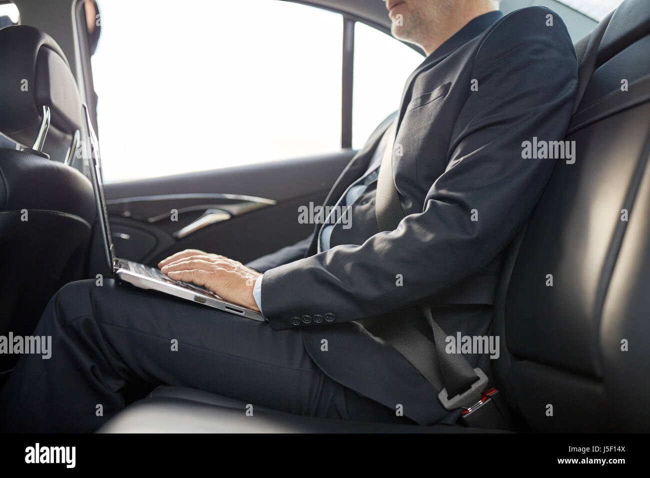 senior businessman with laptop driving in car Stock Photo - Alamy