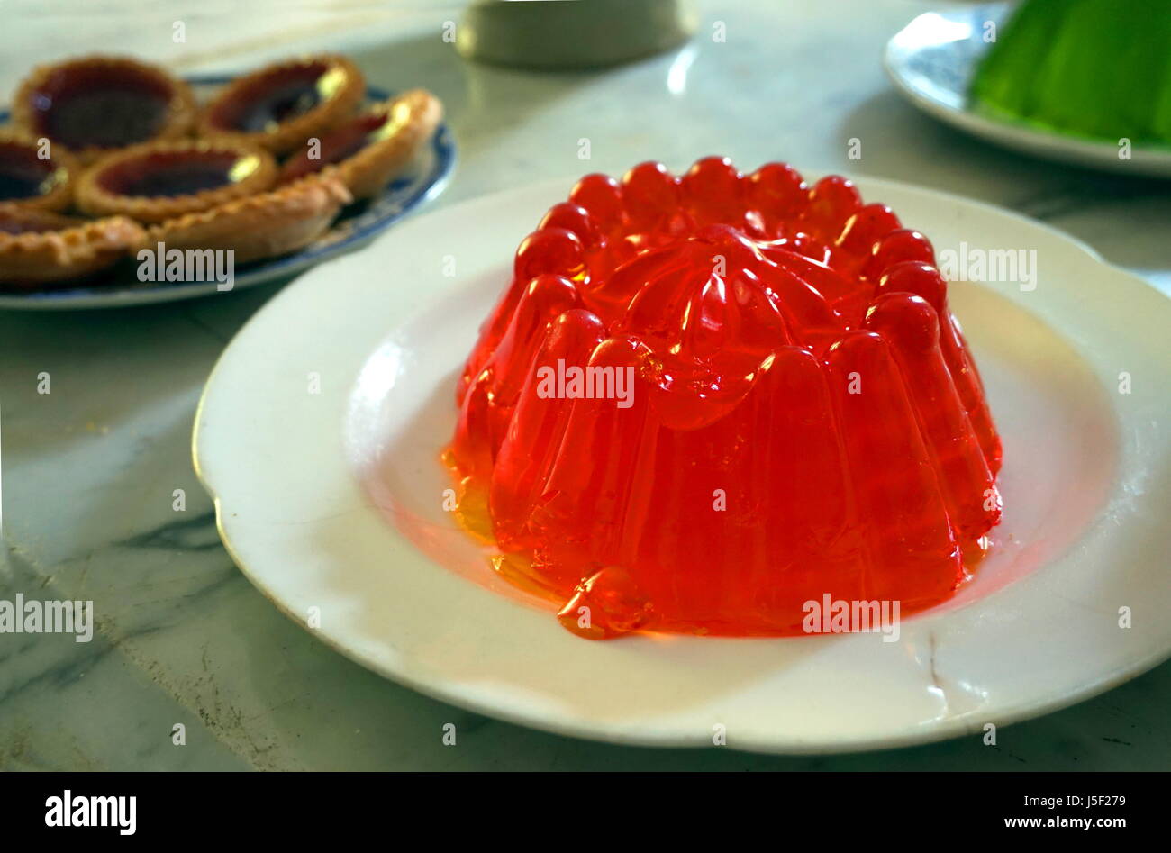 Bright red jelly or jello with tarts and green jelly in the background ...