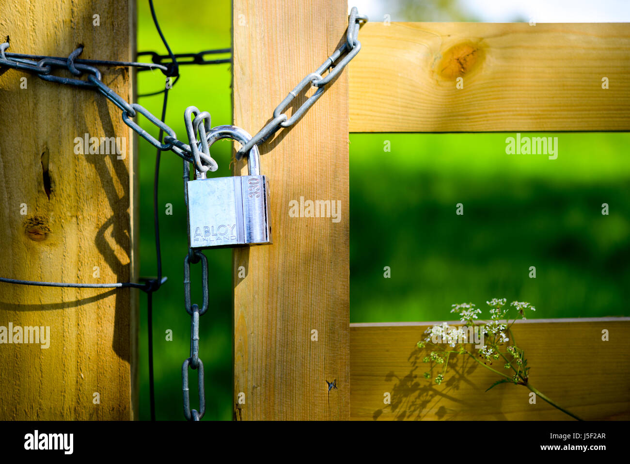 Padlock and chain securing wooden gate to a post Stock Photo - Alamy