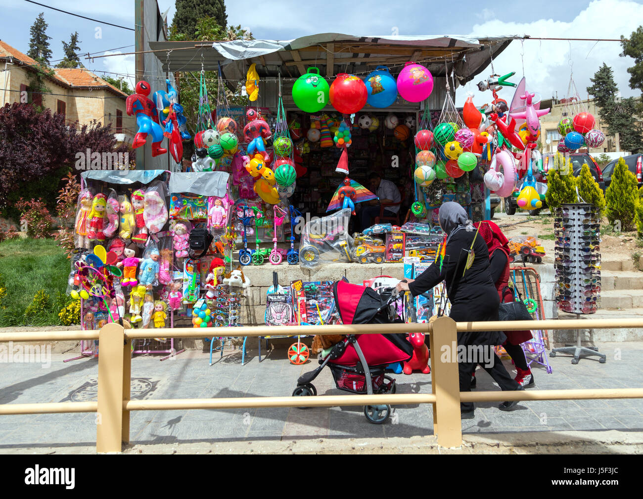 Lebanese woman with a baby-buggy passing in front of a toy shop with ...