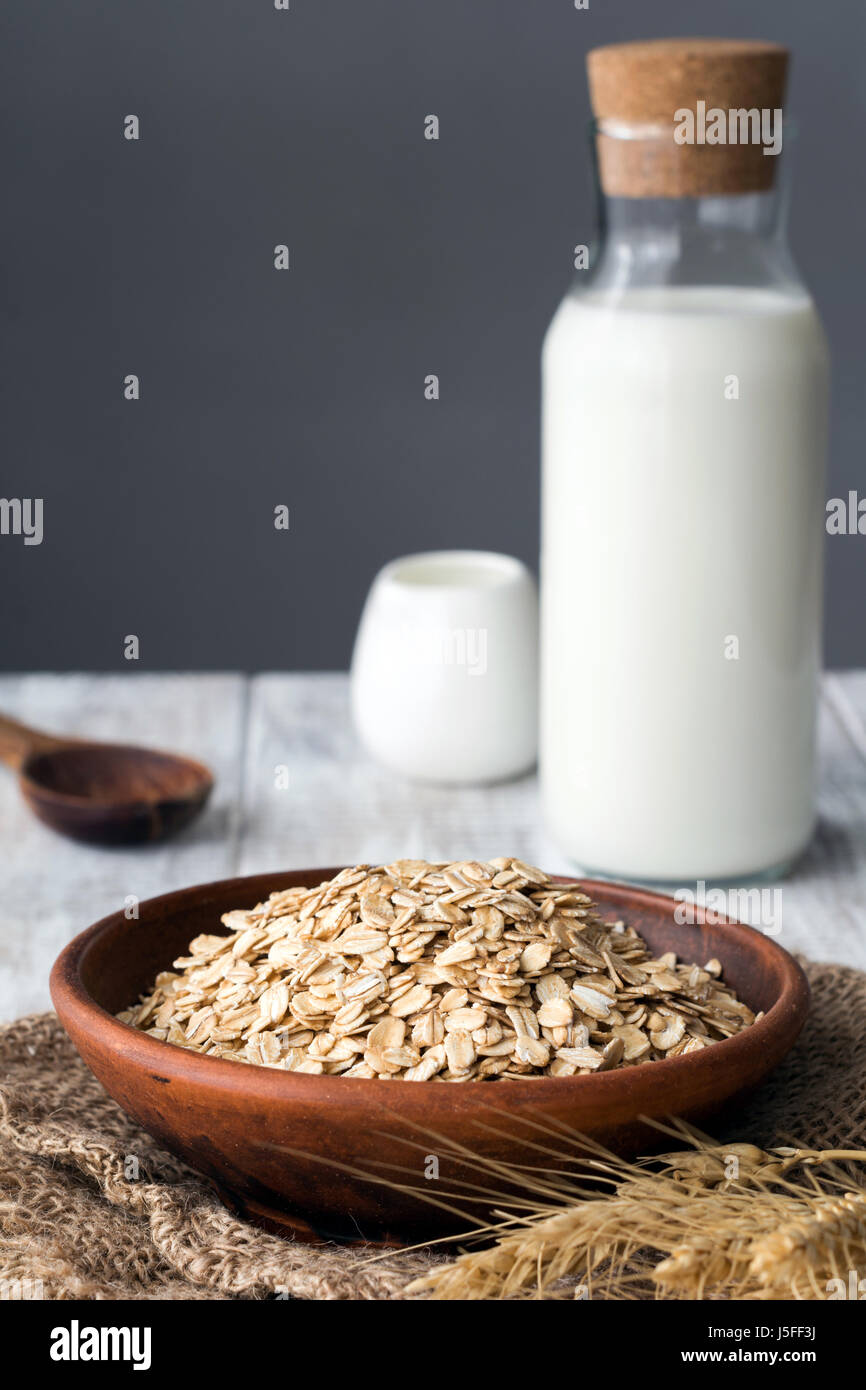 Organic oat flakes, rolled oats in brown ceramic bowl, wheat ears and ...