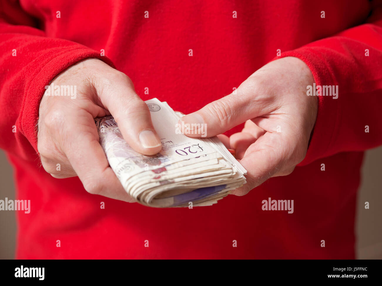 Close up of man person holding English money cash banknotes £20 twenty ...