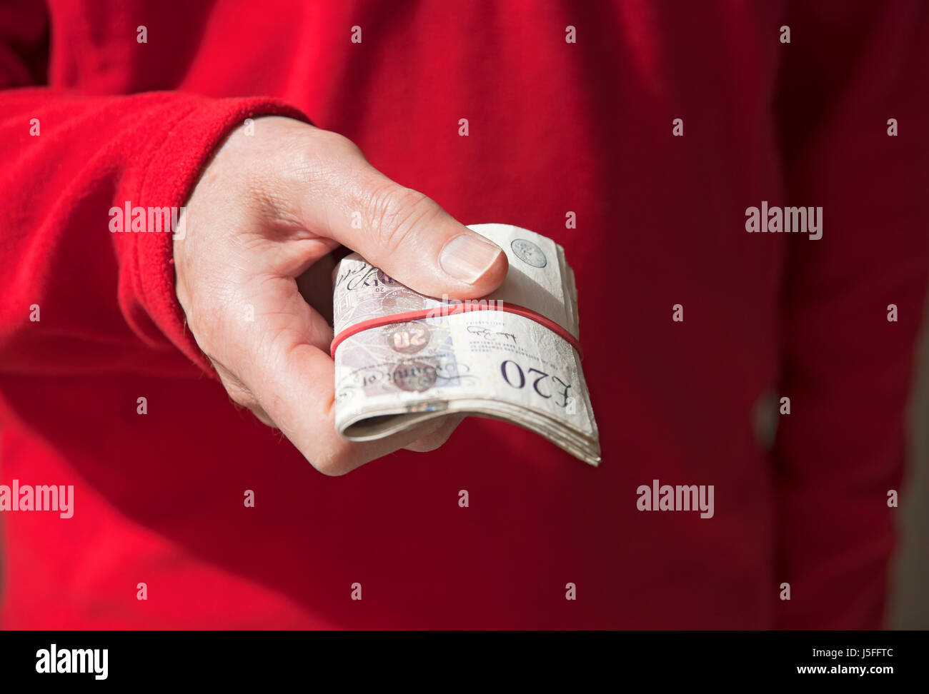 Close up of person man holding English twenty pound notes £20 banknotes ...