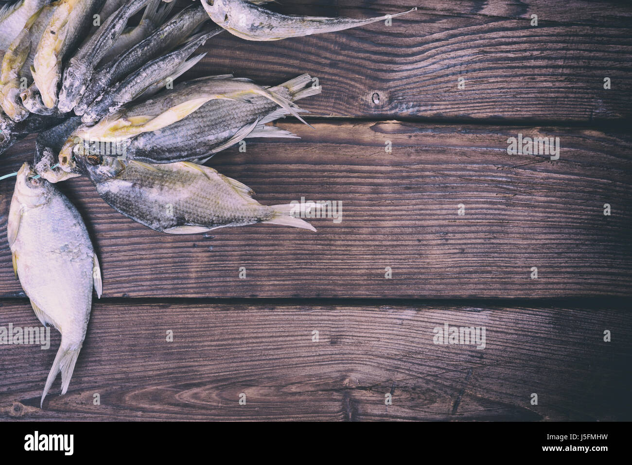 Dried fish tied on a rope, empty space on the right, wooden brown ...