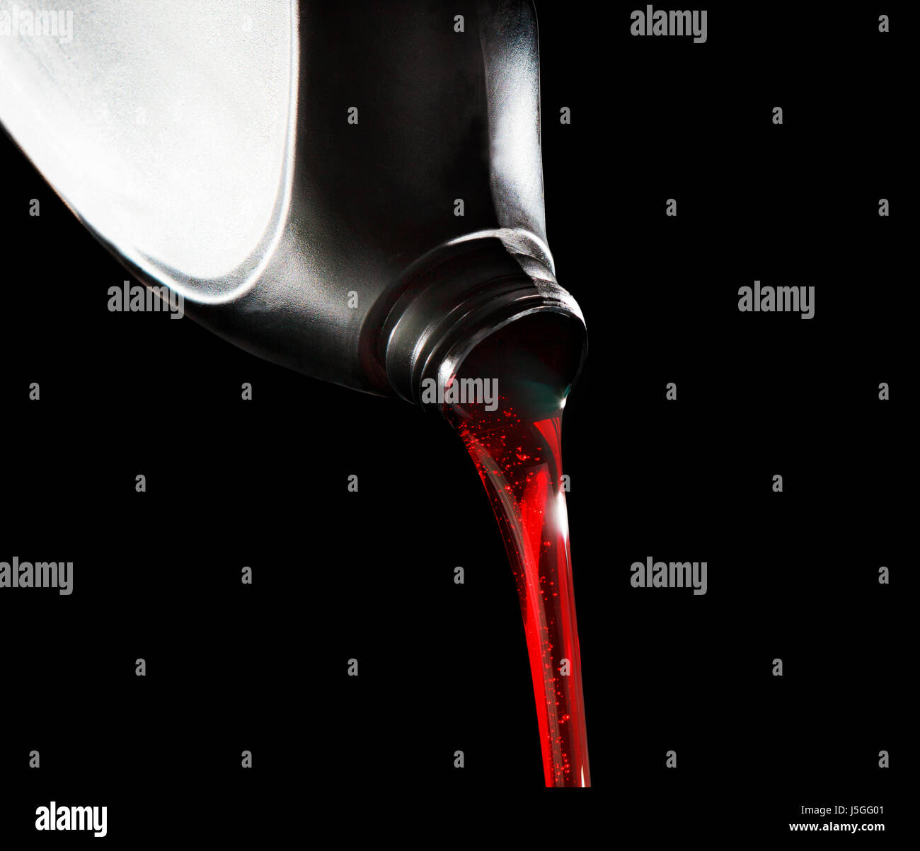 file close up red motor oil pouping from black plastic bottle against ...